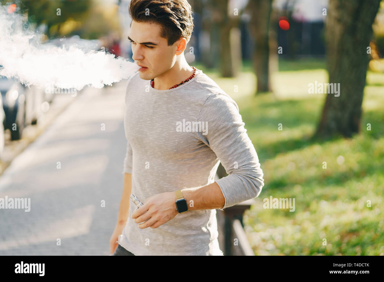 stylish man walking through the city smoking an e-cigarette Stock Photo ...