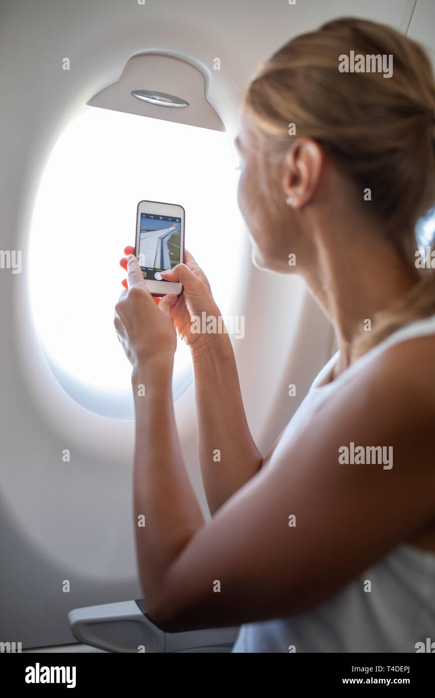 Young woman taking photos during flight in a modern airplane Stock ...