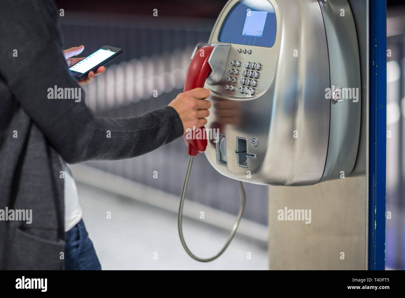 Young woman using a public phone in an airport (color toned image ...