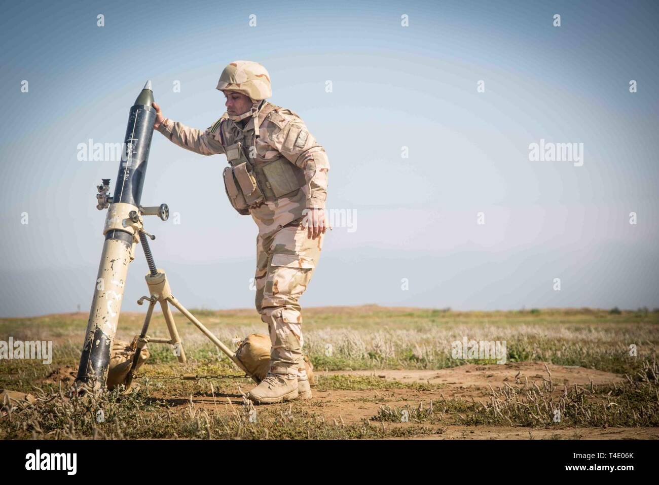 An Iraqi soldier places a mortar shell into a M74 light mortar system ...