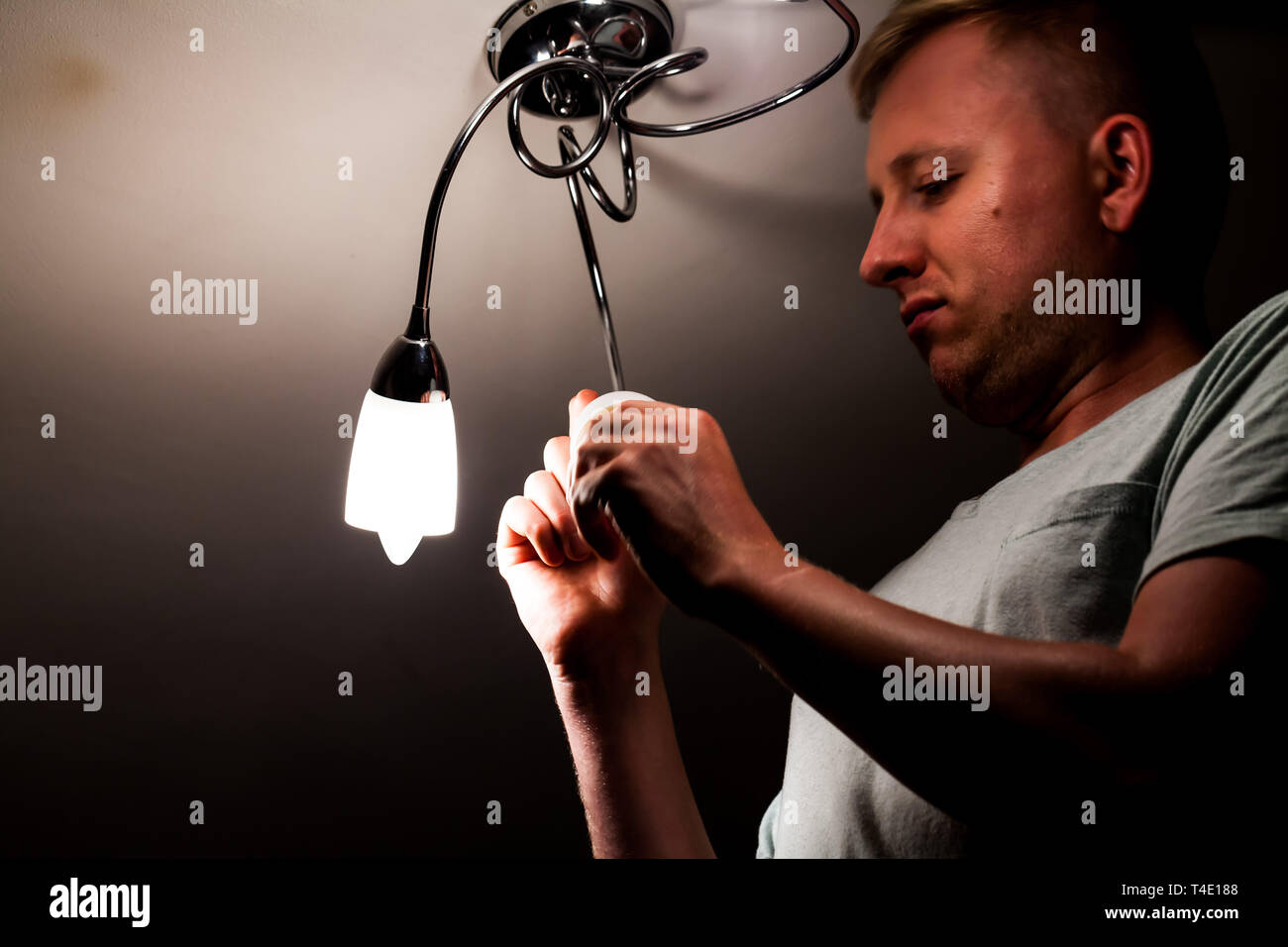 A middle-aged man changes the bulb on the ceiling. A man installs a new ...