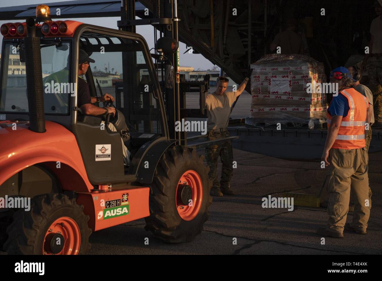 A U.S. Air Force Loadmaster directs a forklift driver to the back of a ...