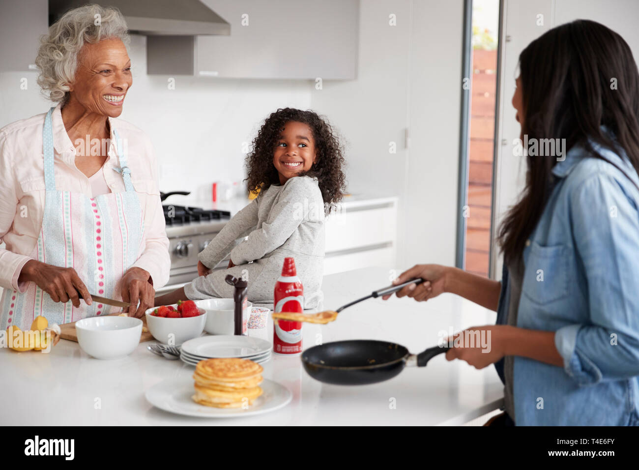 Multi Generation Female Family In Kitchen At Home Making Pancakes ...