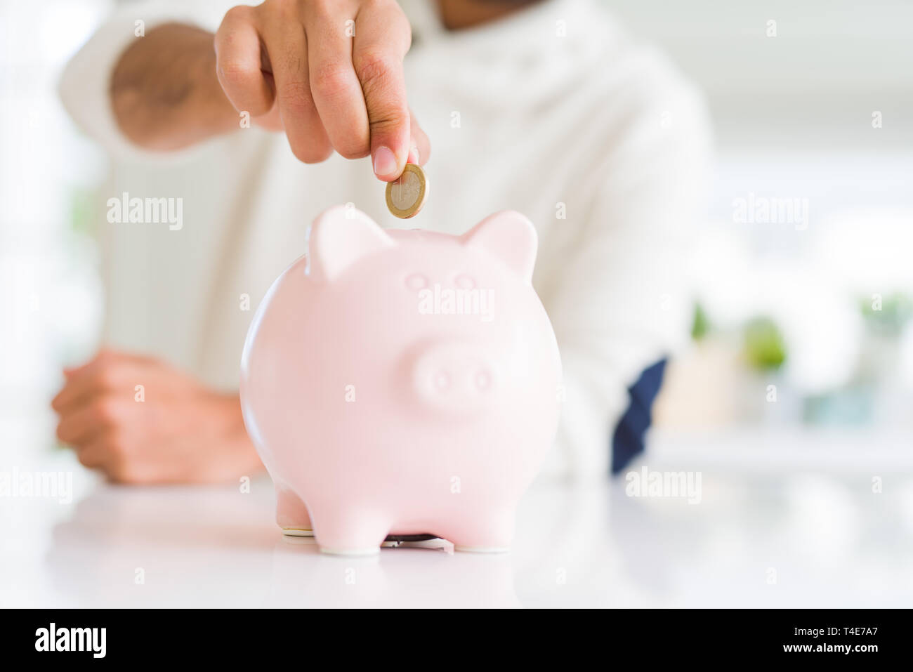 Man putting a coin inside of piggy bank saving for investment Stock ...