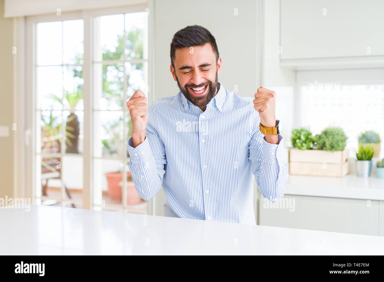 Handsome hispanic business man excited for success with arms raised ...
