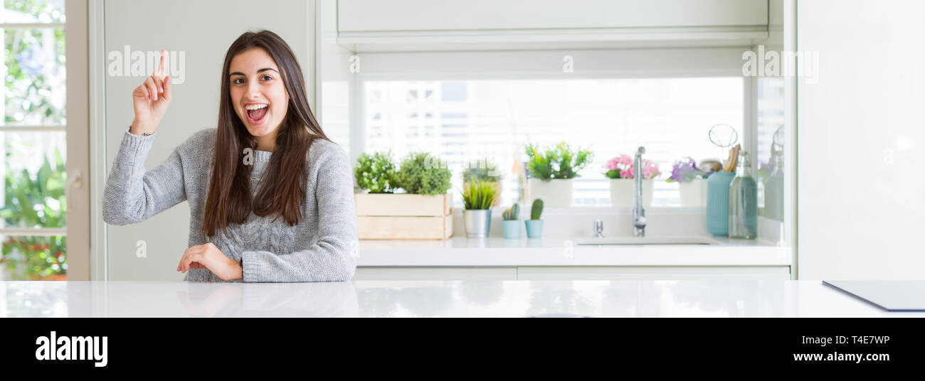 Wide angle picture of beautiful young woman sitting on white table at ...