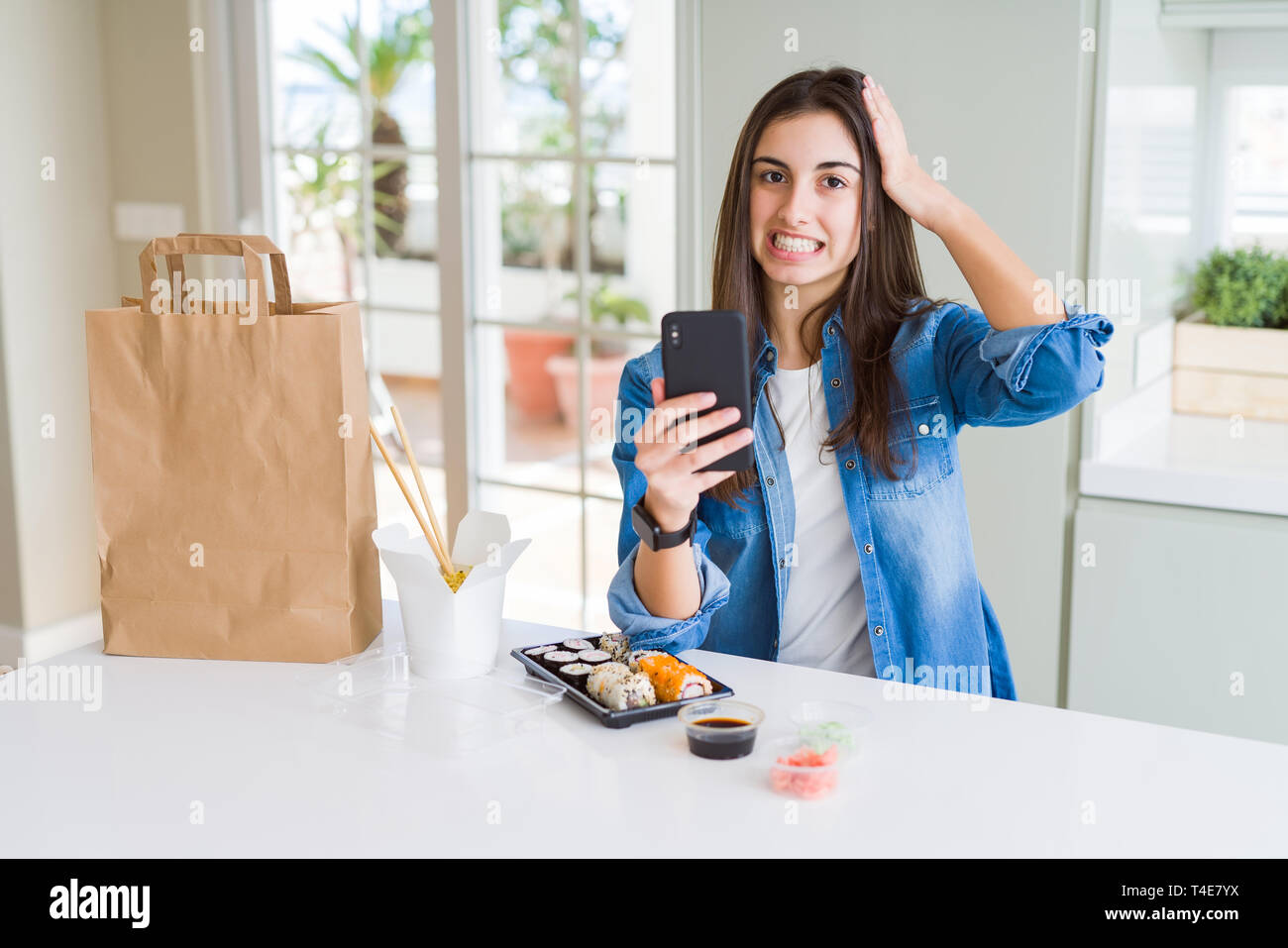 Beautiful young woman ordering food delivery from app using smartphone ...