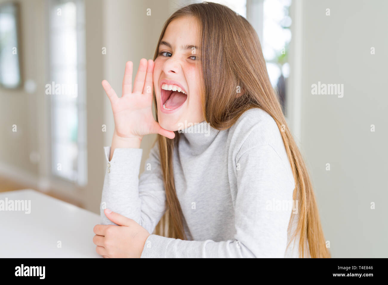 Beautiful young girl kid wearing turtleneck sweater shouting and ...