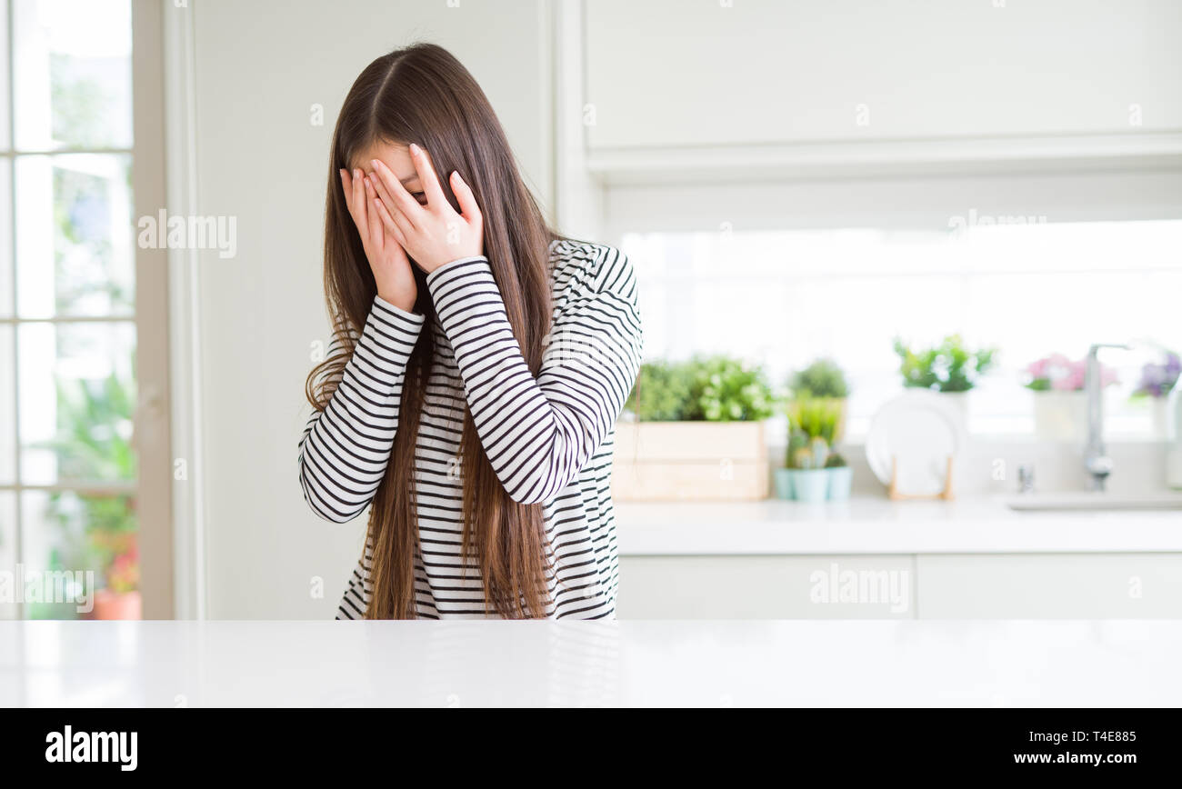 Beautiful Asian woman wearing stripes sweater with sad expression ...