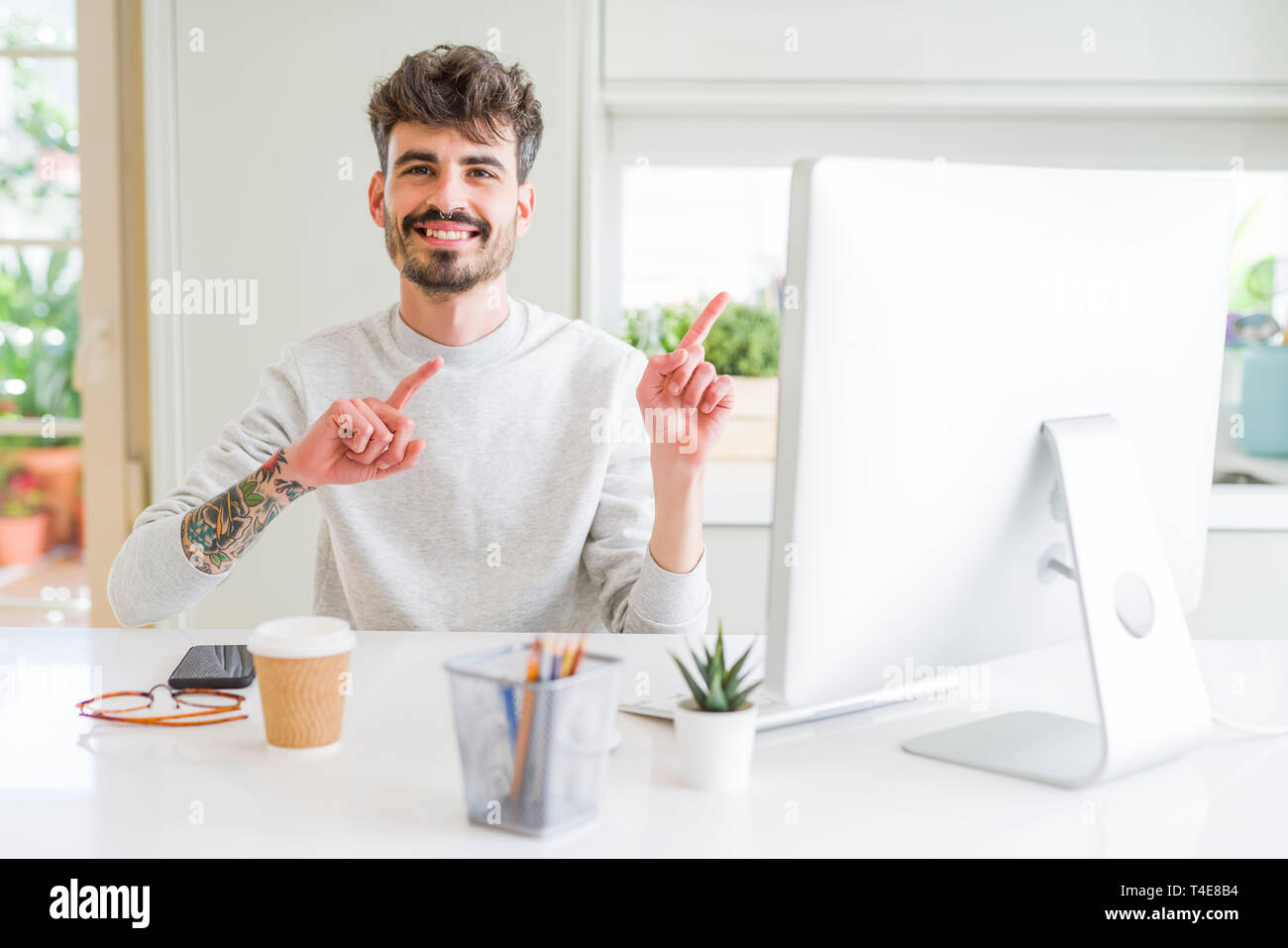 Young man working using computer smiling and looking at the camera ...