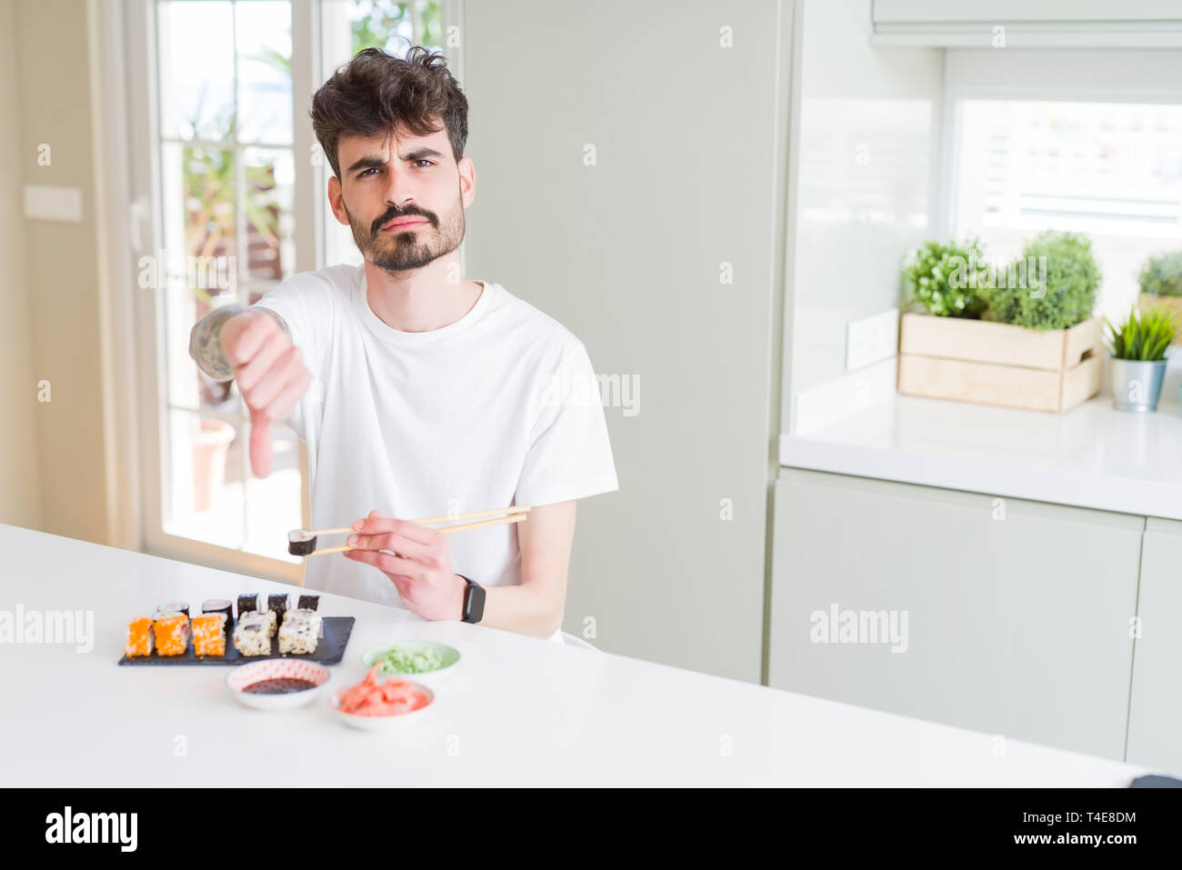 Young man eating asian sushi from home delivery with angry face ...