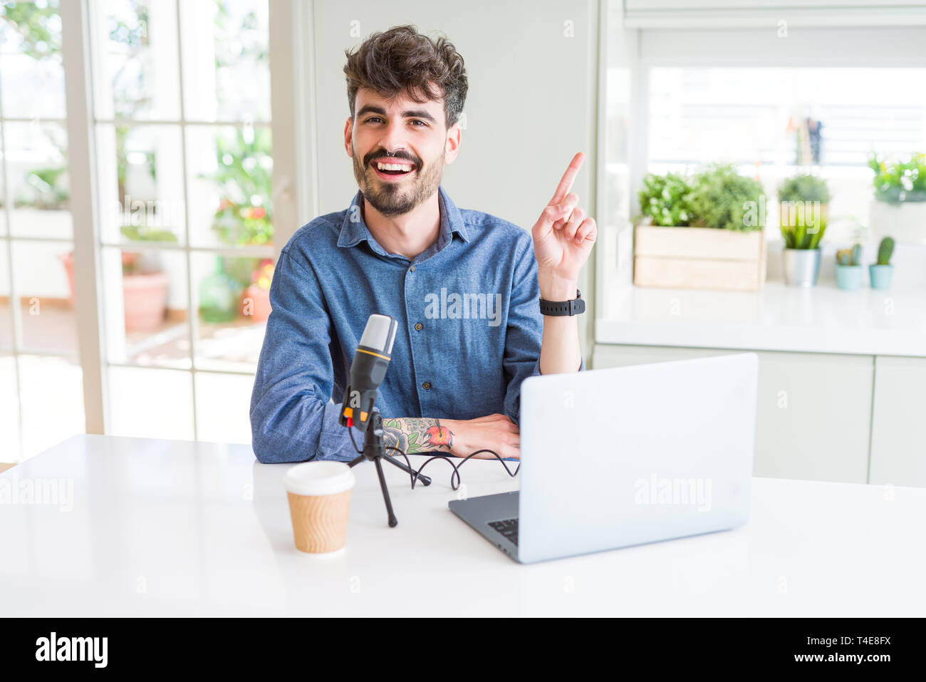 Young man recording podcast using microphone and laptop with a big ...