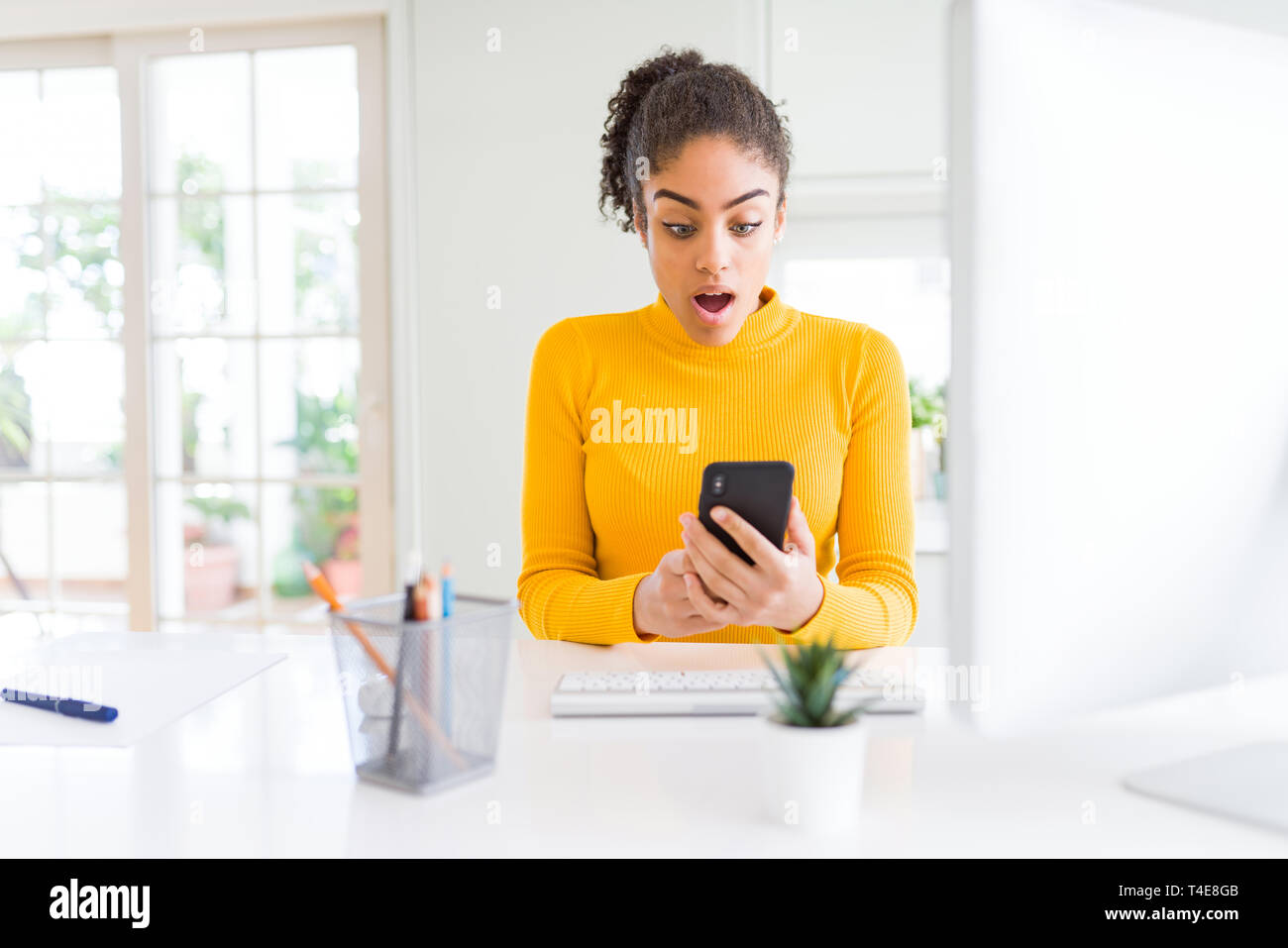 Young african american girl working using computer and smartphone ...