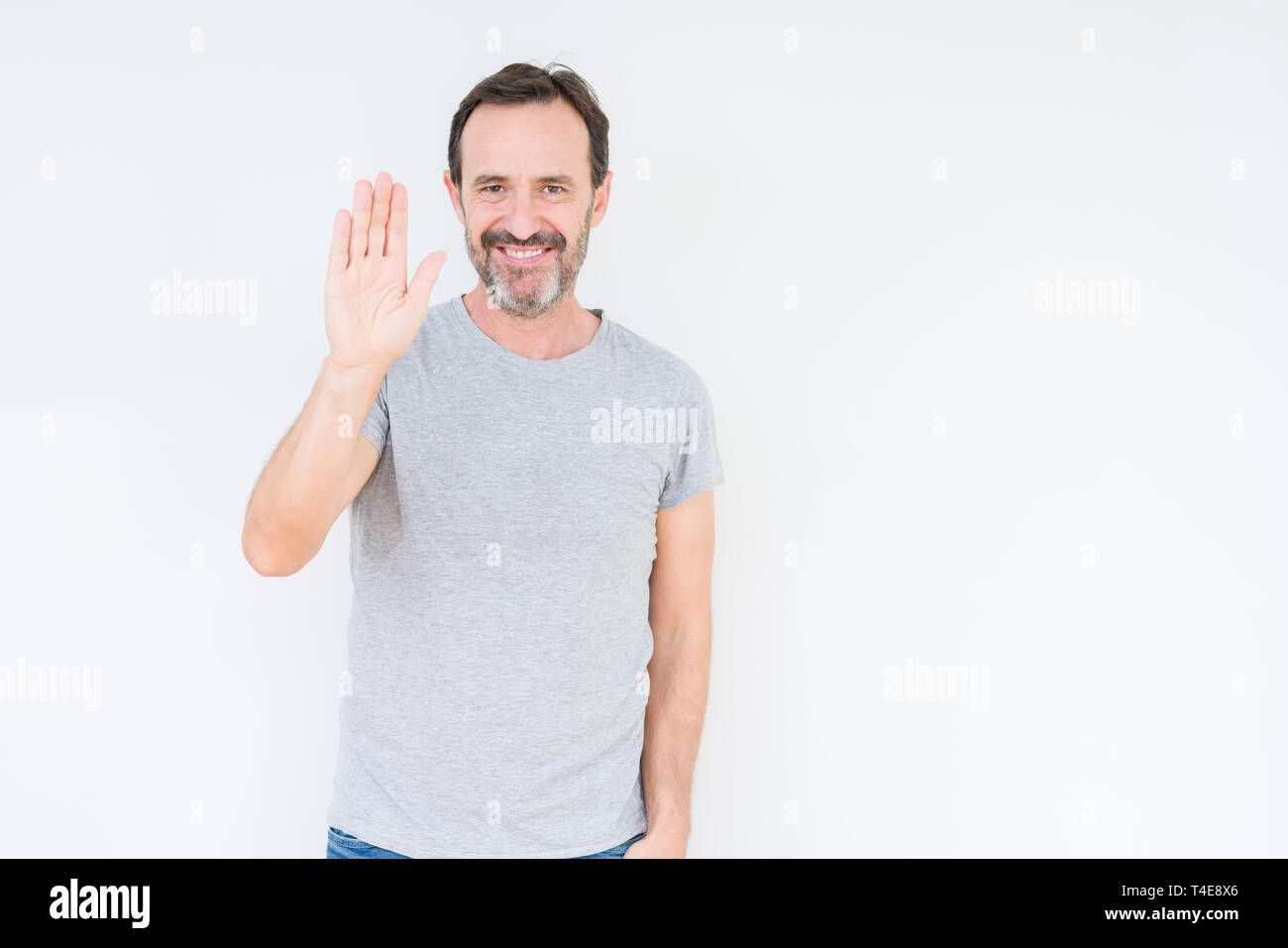 Handsome senior man over isolated background Waiving saying hello happy ...