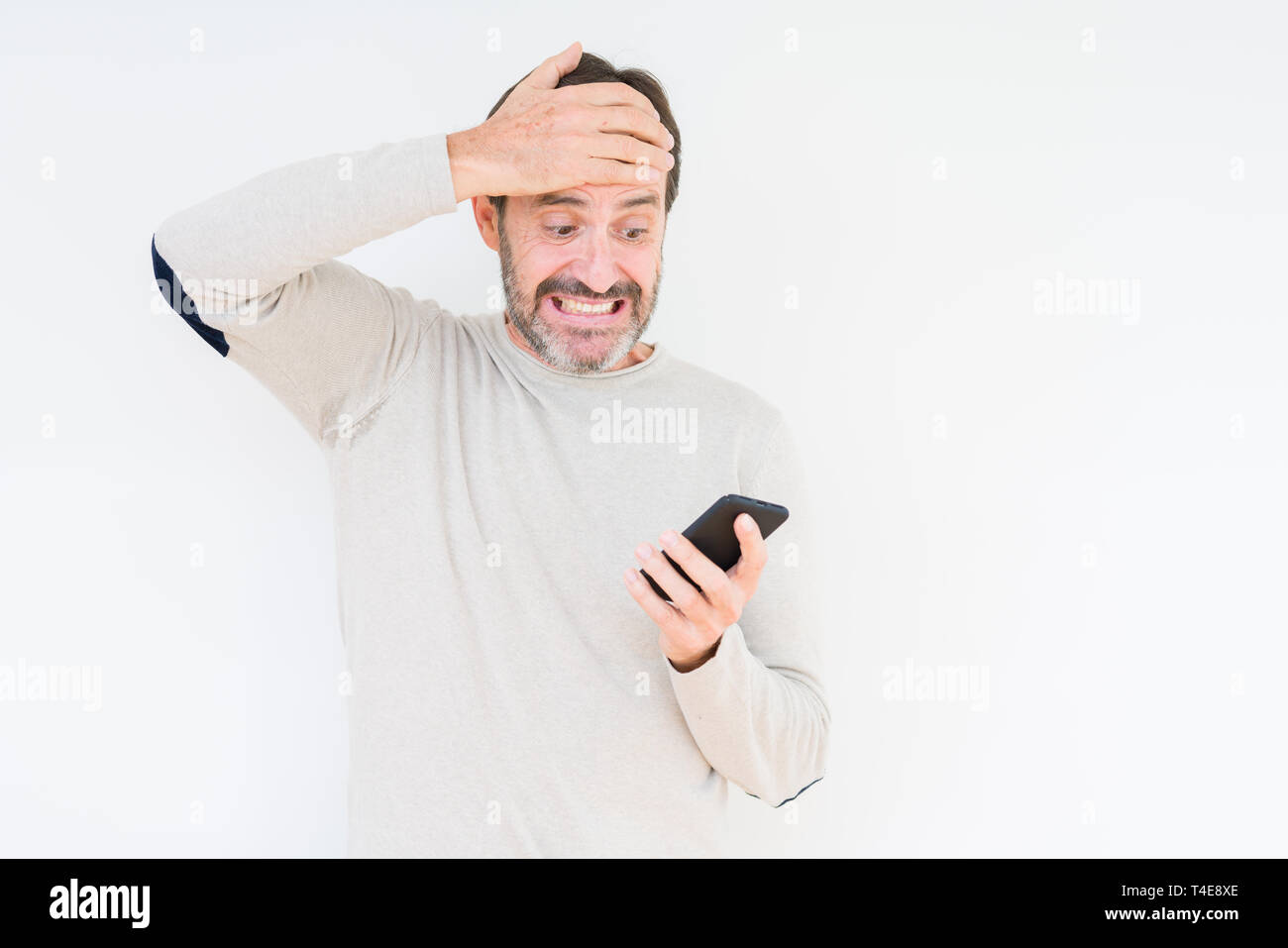 Senior man using smartphone over isolated background stressed with hand ...