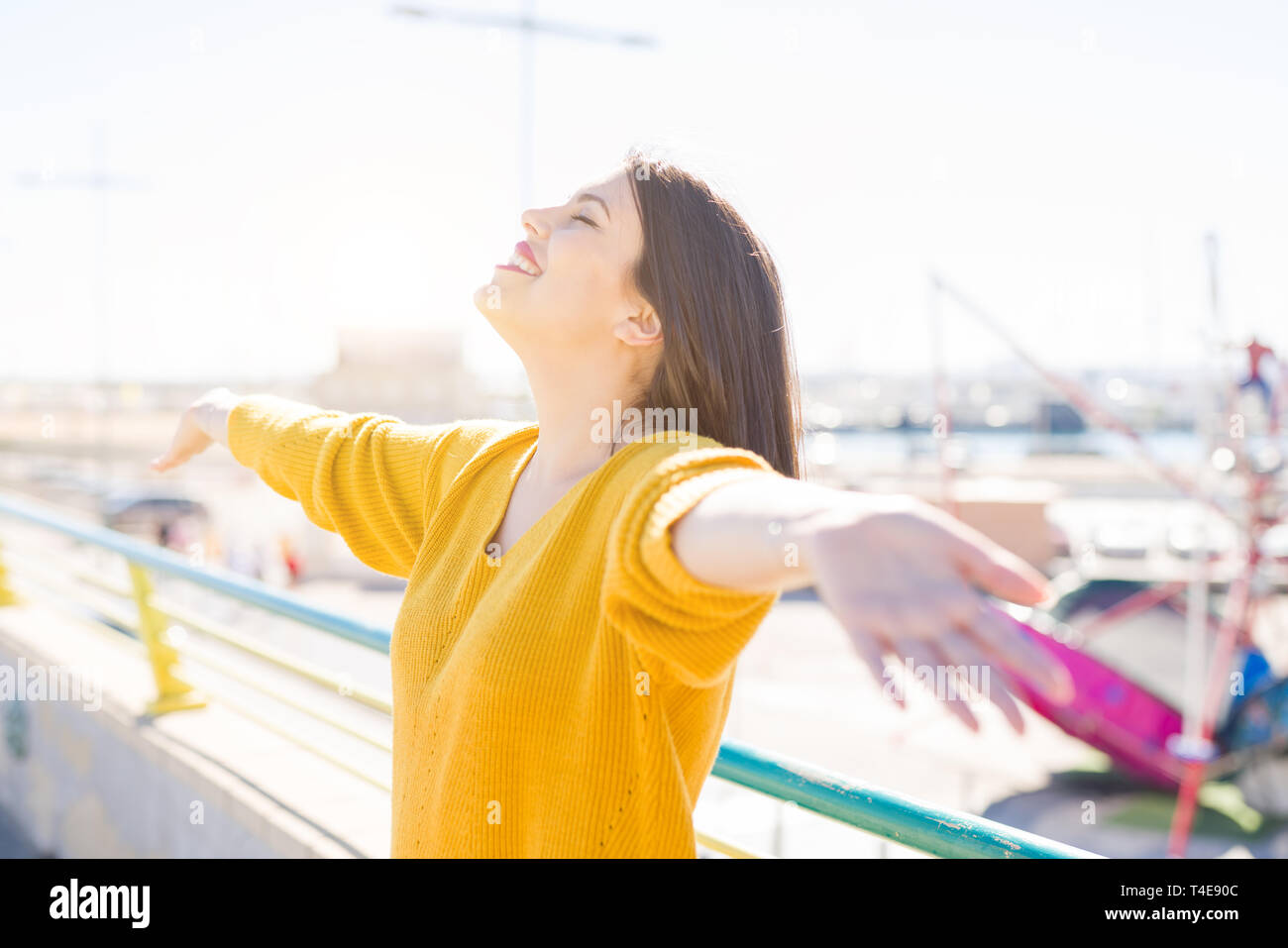 Beautiful young woman smiling with closed eyes and open arms enjoying ...