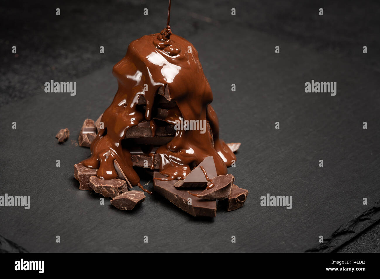close up of chocolate pieces pile or heap and melted chocolate syrup on ...