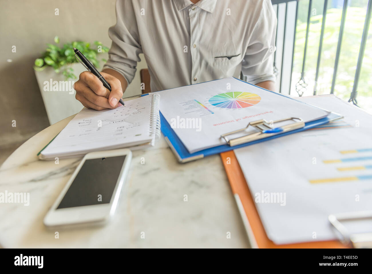 Young man reading financial data on document and writing notes Stock ...