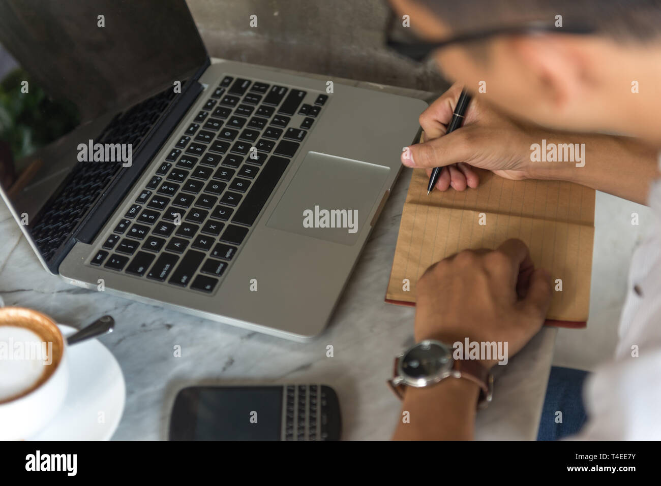 Side view of Asian man writing into notes Stock Photo - Alamy