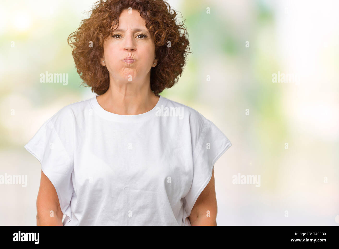 Beautiful middle ager senior woman wearing white t-shirt over isolated ...