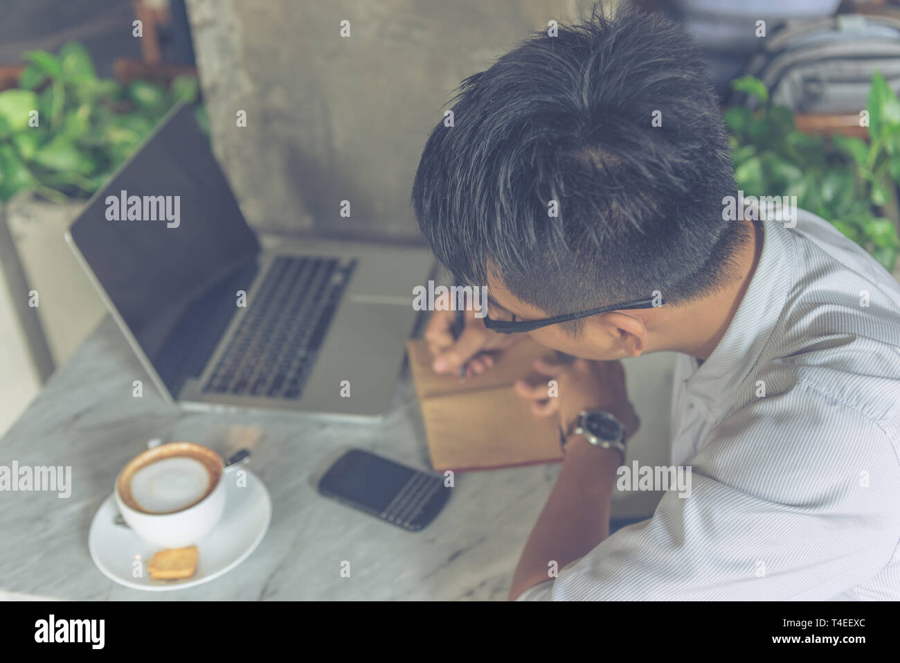 Asian man writing notes in the coffee shop Stock Photo - Alamy
