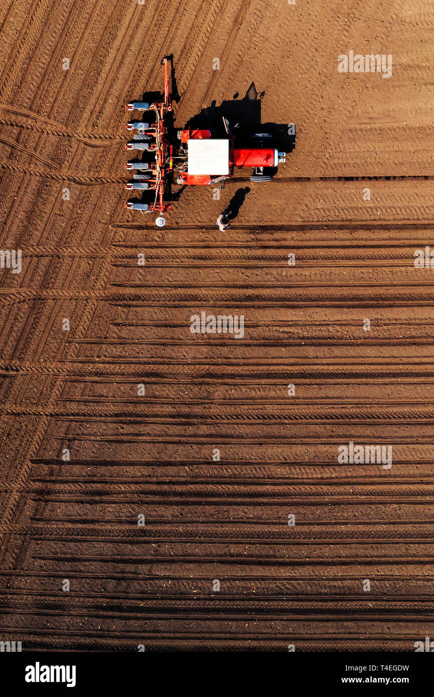Aerial view of farmer and tractor with crop seeder mounted during corn ...