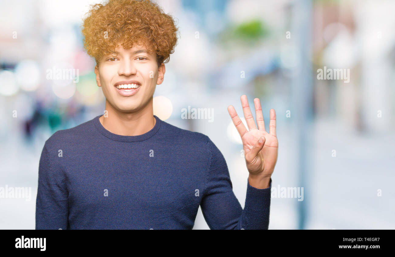 Young handsome man with afro hair showing and pointing up with fingers ...