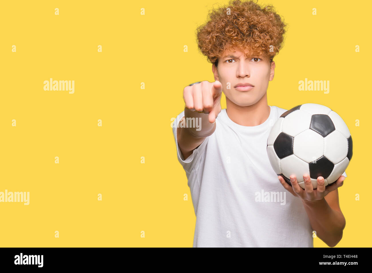 Young handsome man holding soccer football ball pointing with finger to ...