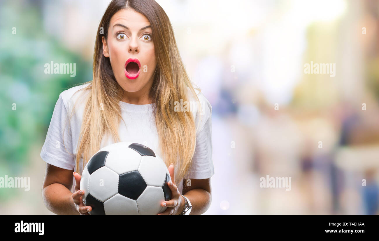 Young beautiful woman holding soccer ball over isolated background ...