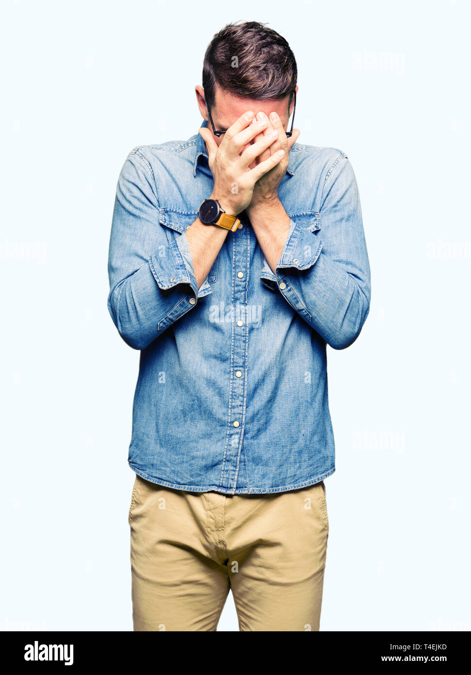 Handsome man wearing glasses with sad expression covering face with ...