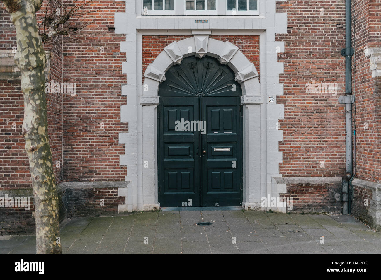 Arch entry door on red brick wall background Stock Photo - Alamy