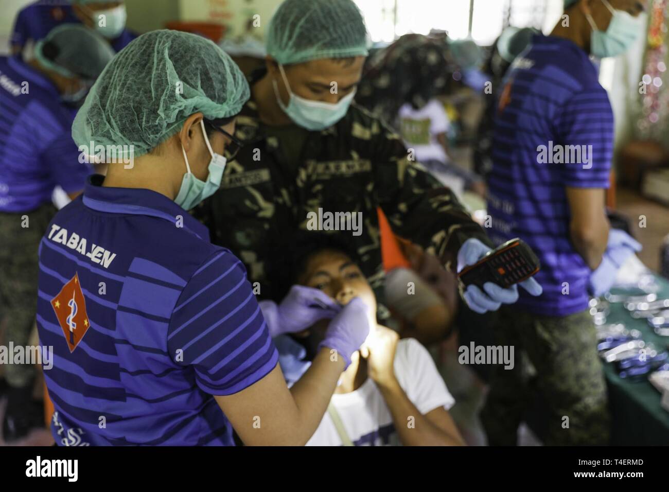 Philippine Army 1st Lt. Mary Tabajen inspects a boy's teeth during a ...