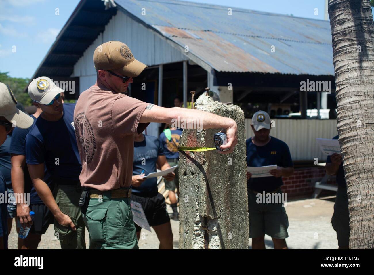 U.S. Navy Petty Officer 2nd Class Robert Norton measures the size of a ...