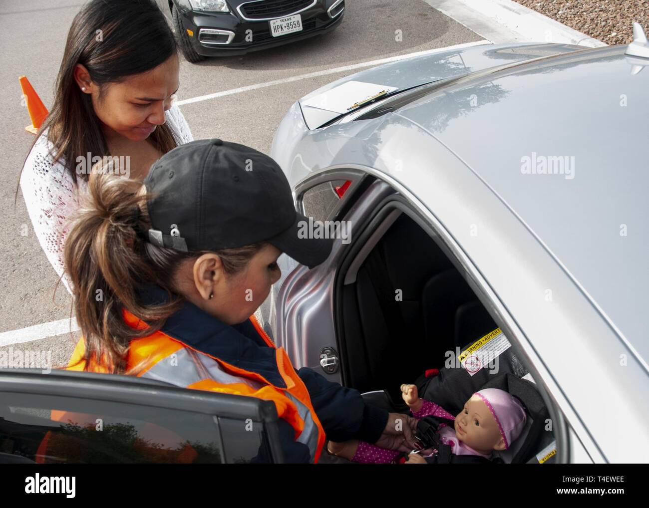 A certified child passenger safety technician buckles a doll to ...