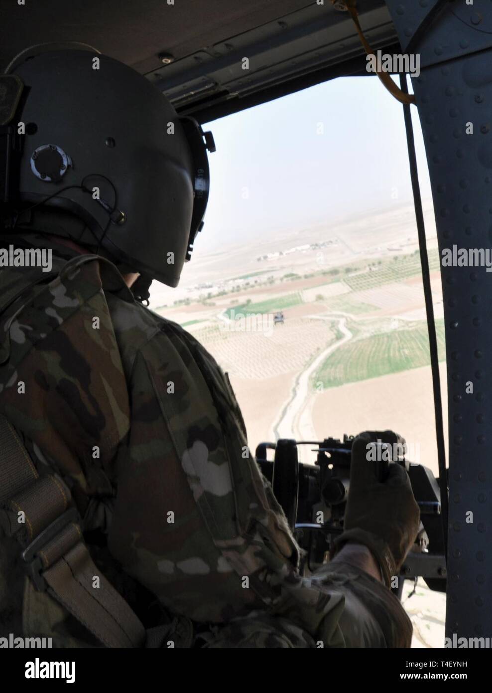 An Army National Guard UH-60 Blackhawk helicopter gunner flies over ...