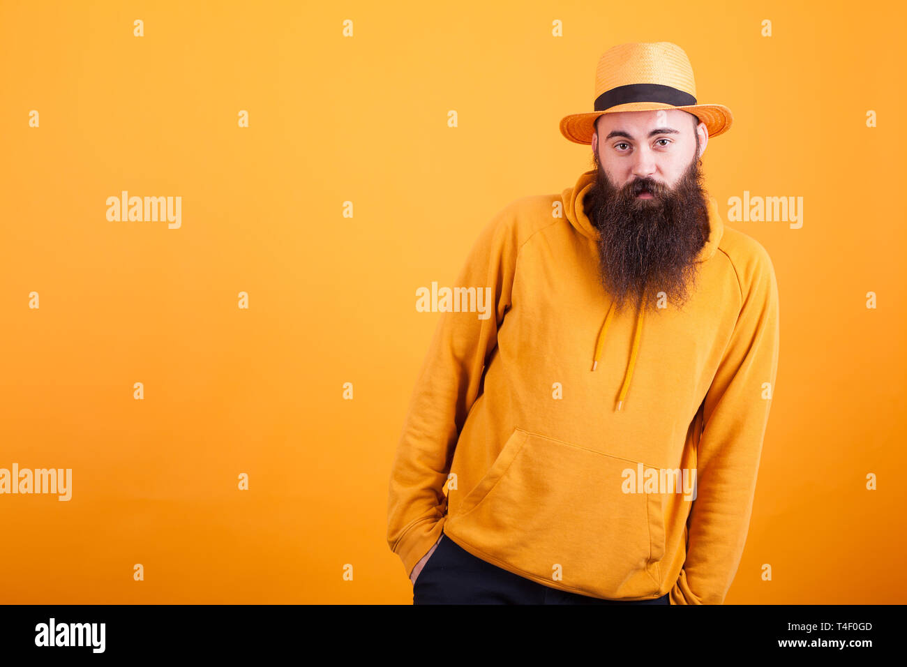 Cool bearded hipster with orange hat holding hands in his pockets over ...