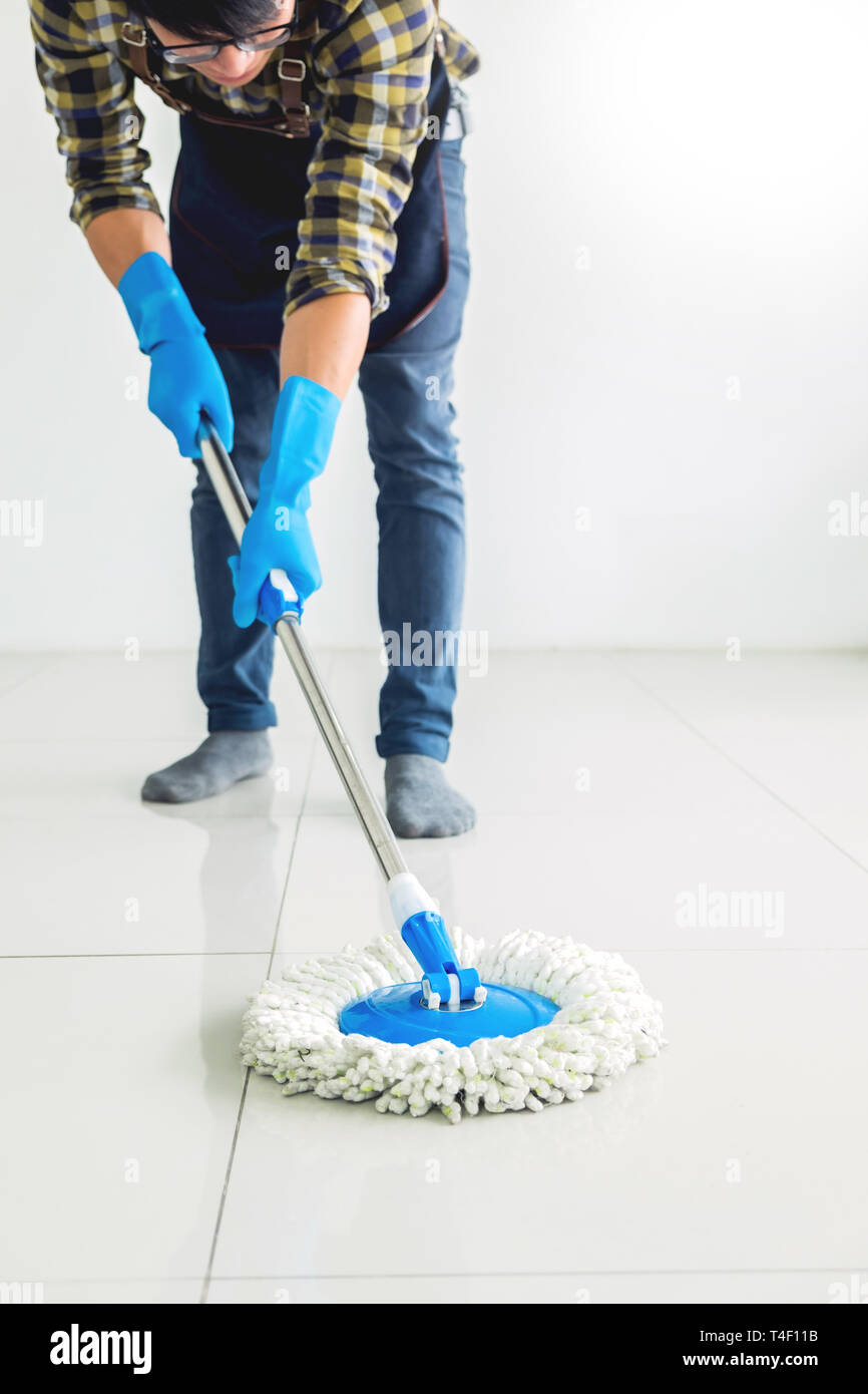 Young housekeeper cleaning floor mobbing holding mop and plastic bucket ...