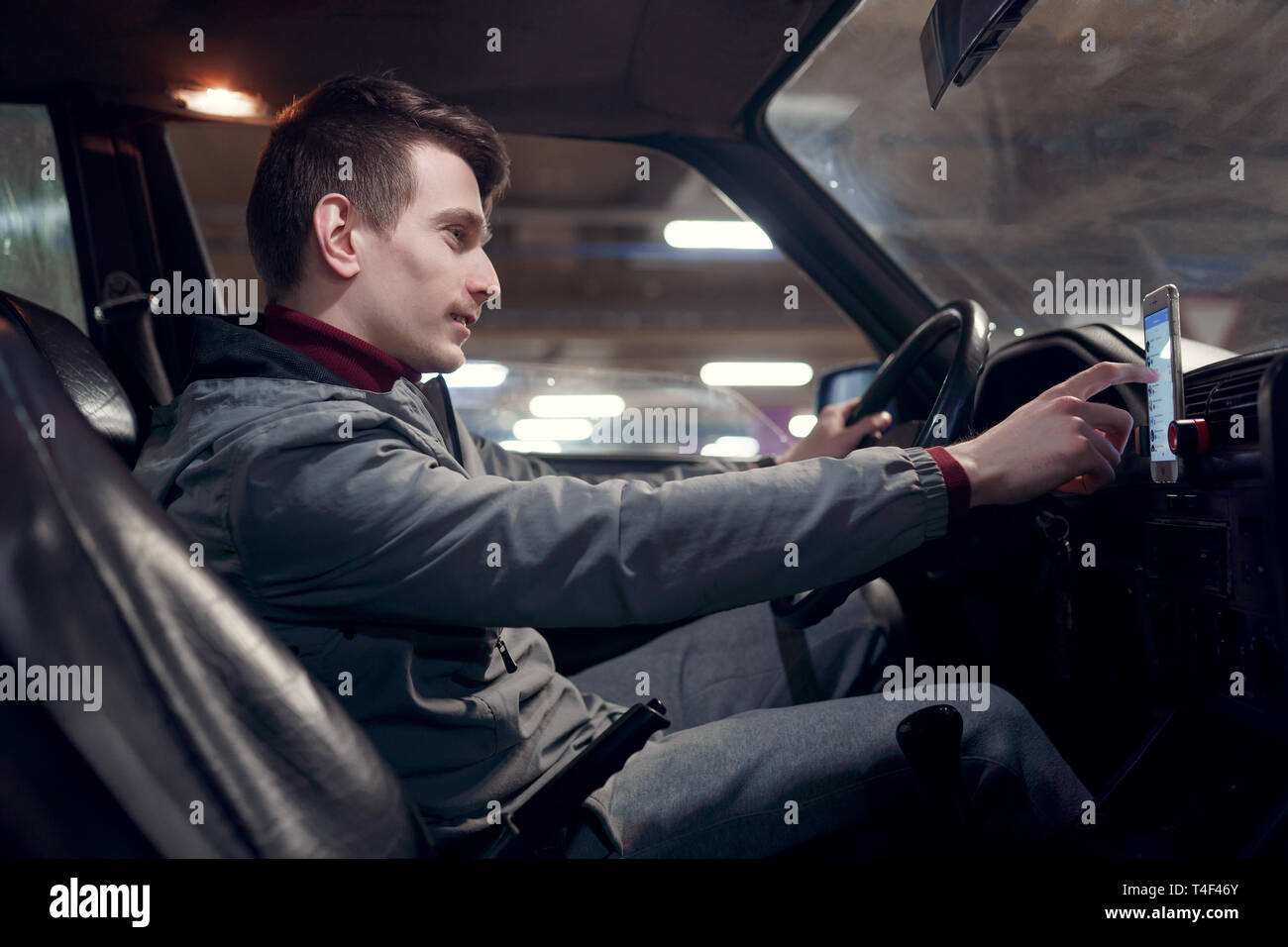 Side photo of male driver setting up navigator while sitting in car ...