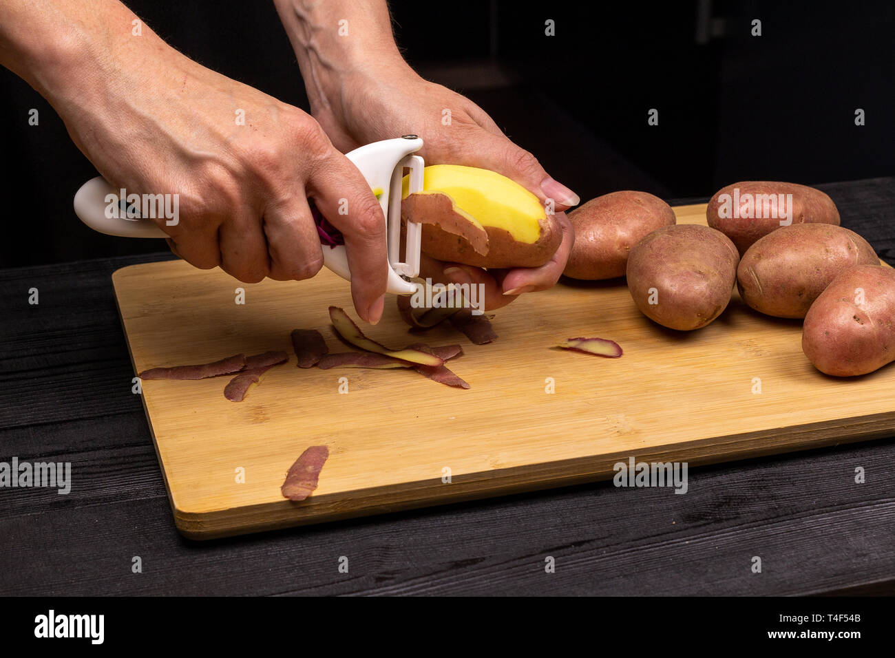 The process of cleaning the potatoes with a special knife peeler. The ...