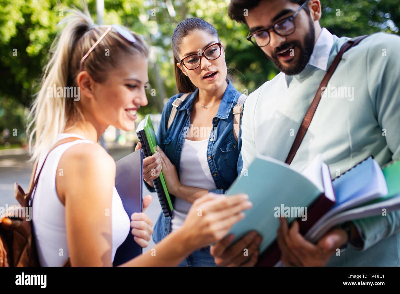 Happy young university students friends studying with books at ...