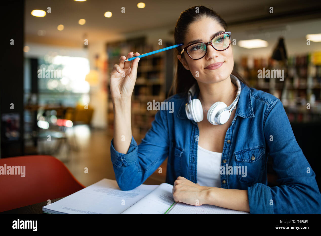 Beautiful student girl learning in a library Stock Photo - Alamy