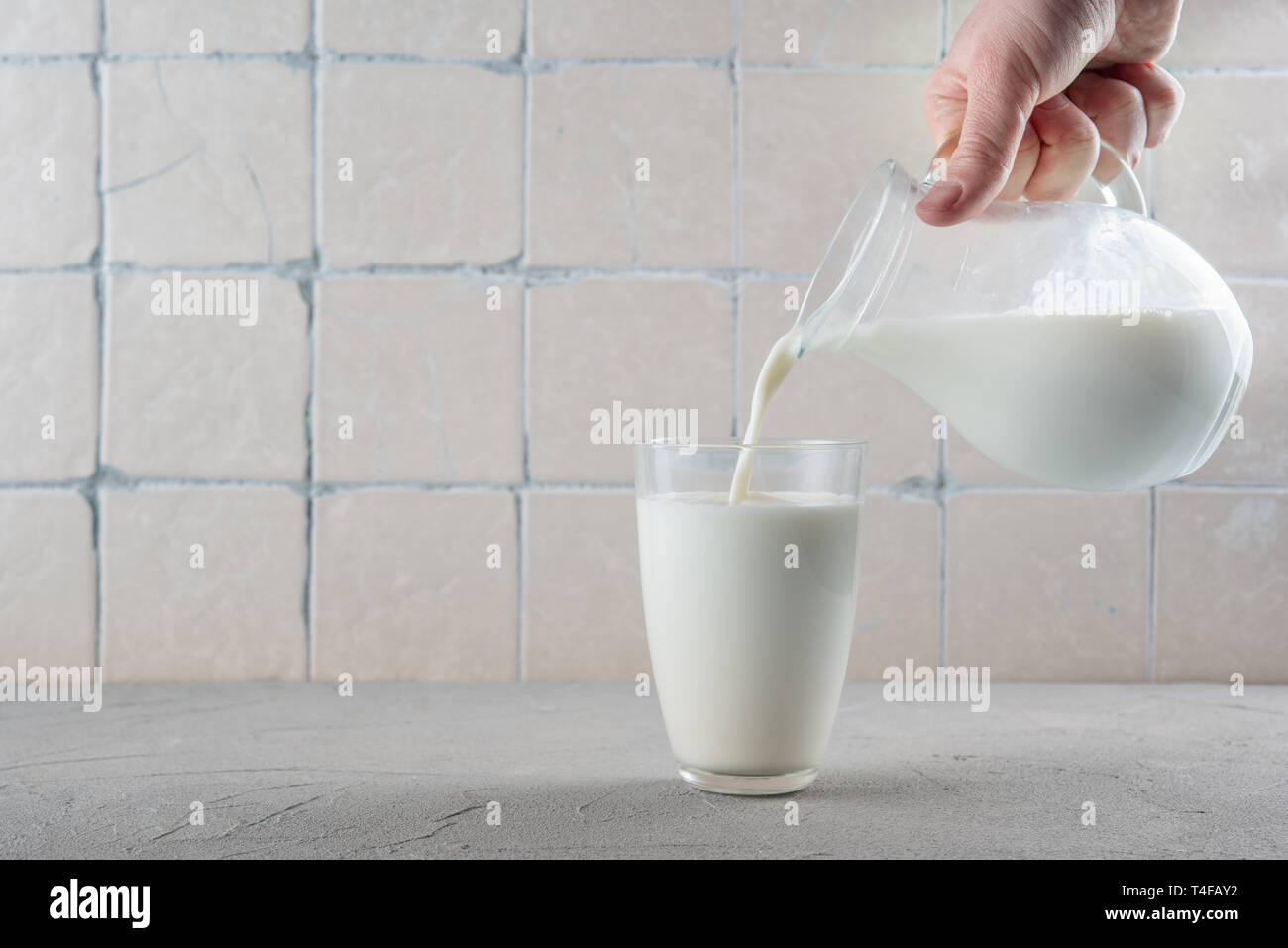 Pouring milk on the kitchen background with ceramic tiles Stock Photo ...