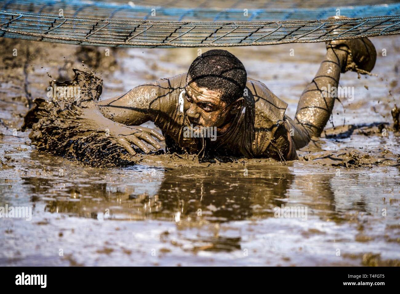 A participant of the 7th Annual Rugged Terrain Obstacle Run low crawls ...