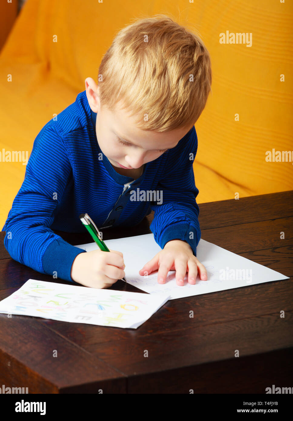 Happy childhood. Blond boy child kid with pen writing on piece of paper ...