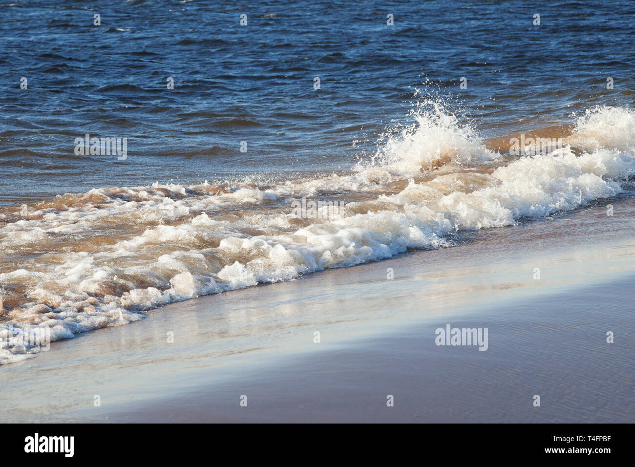 Dramatic wave crashing on the shoreline, with wind blown spray. Water ...