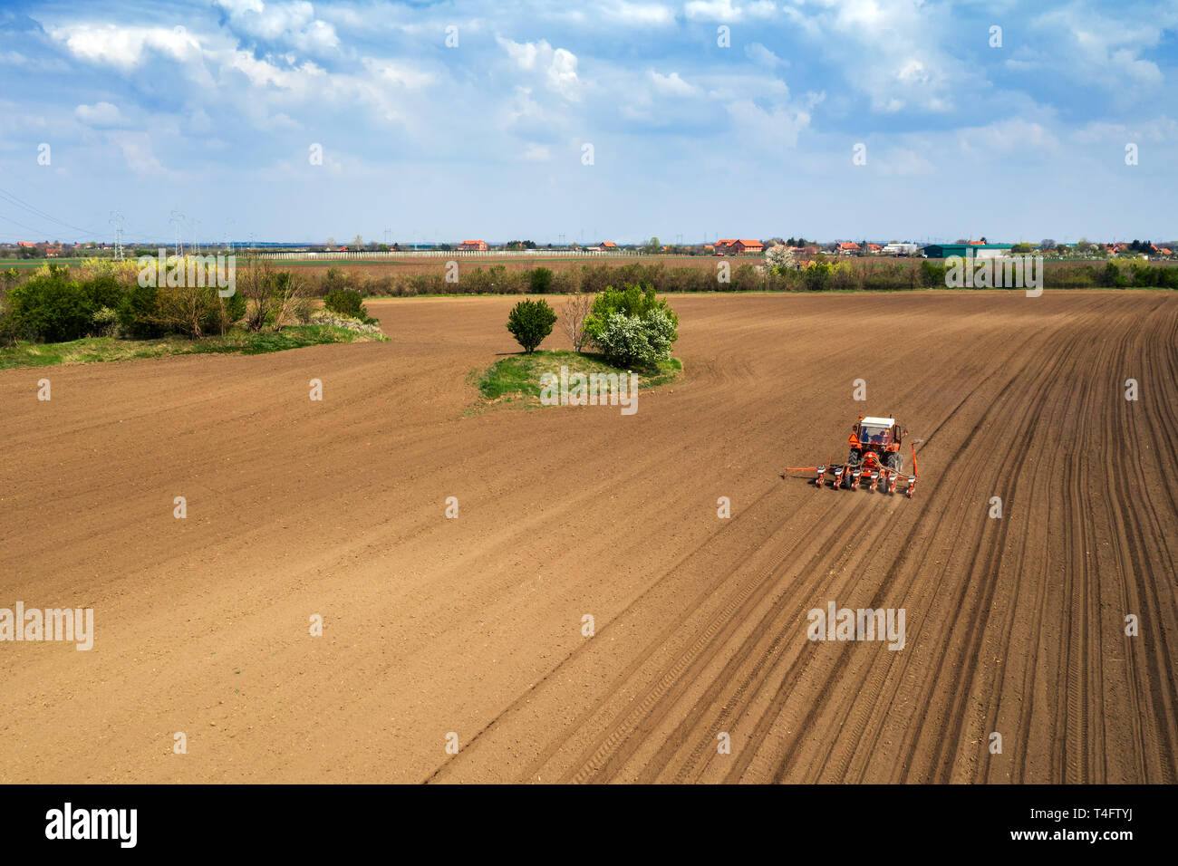 Aerial view of tractor sowing and planting corn in field, agricultural ...