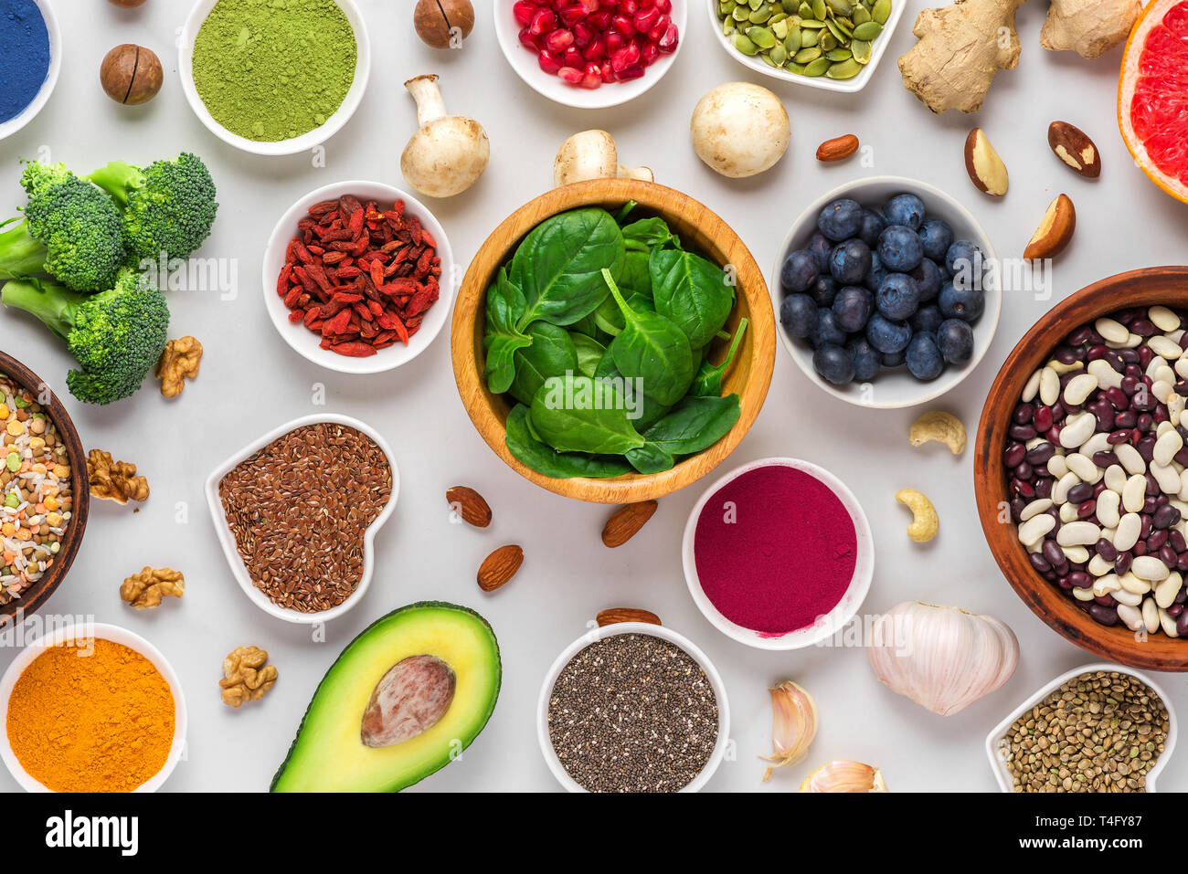 various superfoods on white marble background. vegetables, matcha, acai ...