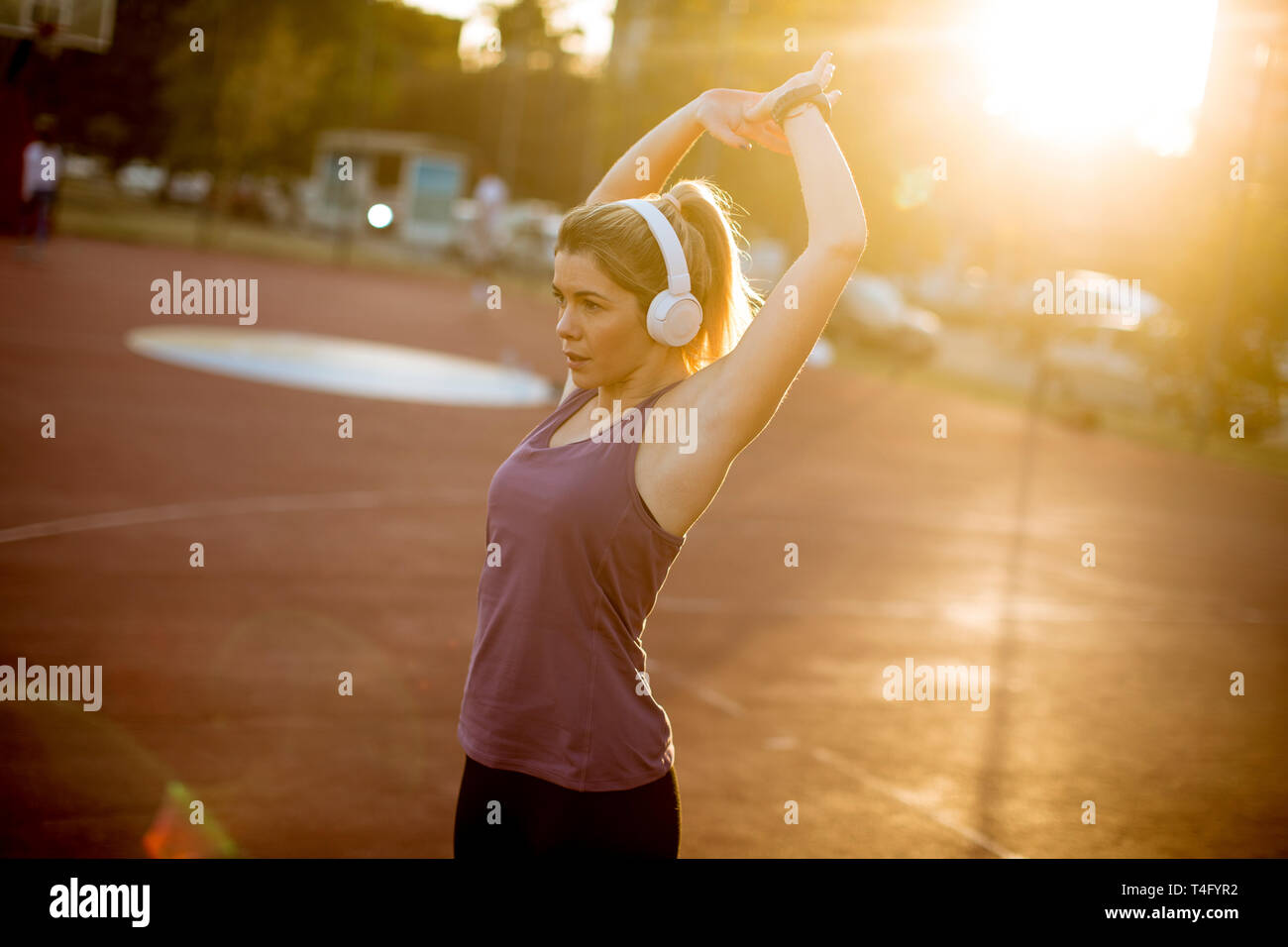 Slender fit blonde woman doing stretching before workout on court Stock ...