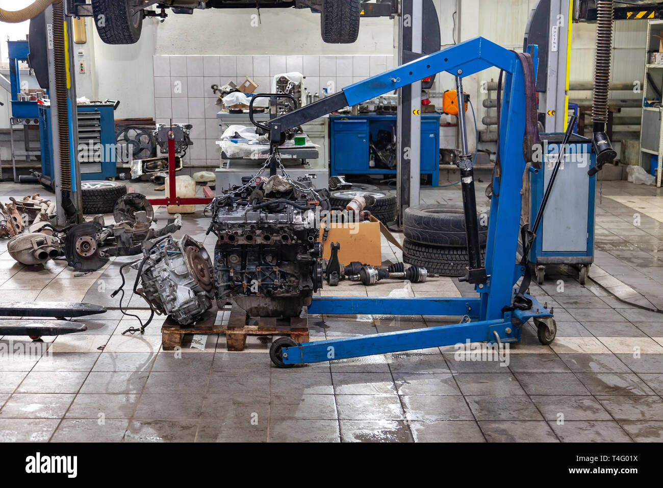 A sports car raised on a lift for repair and under it a detached engine ...