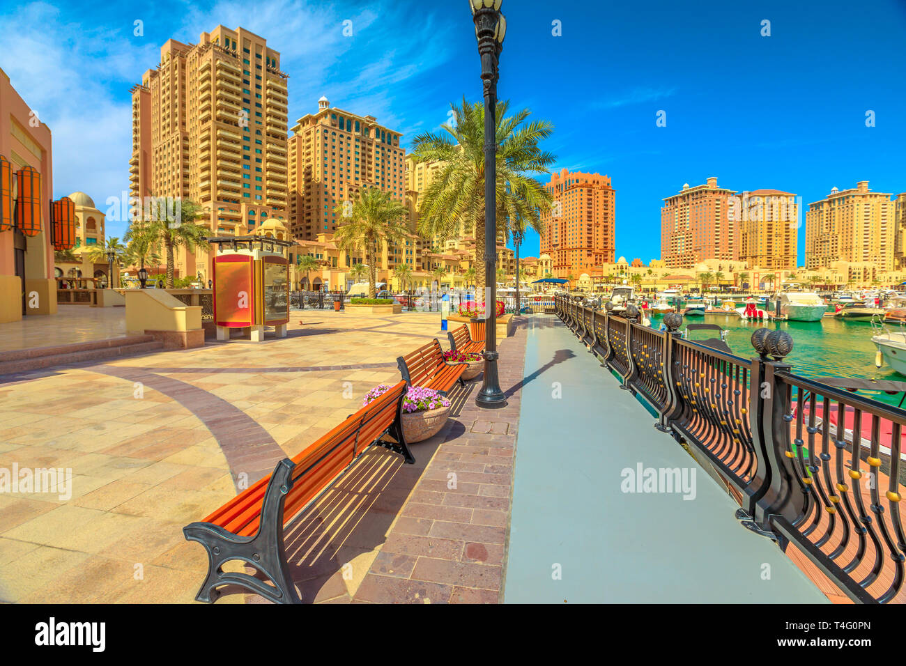 Benches and palm trees along marina walkway promenade in Porto Arabia ...